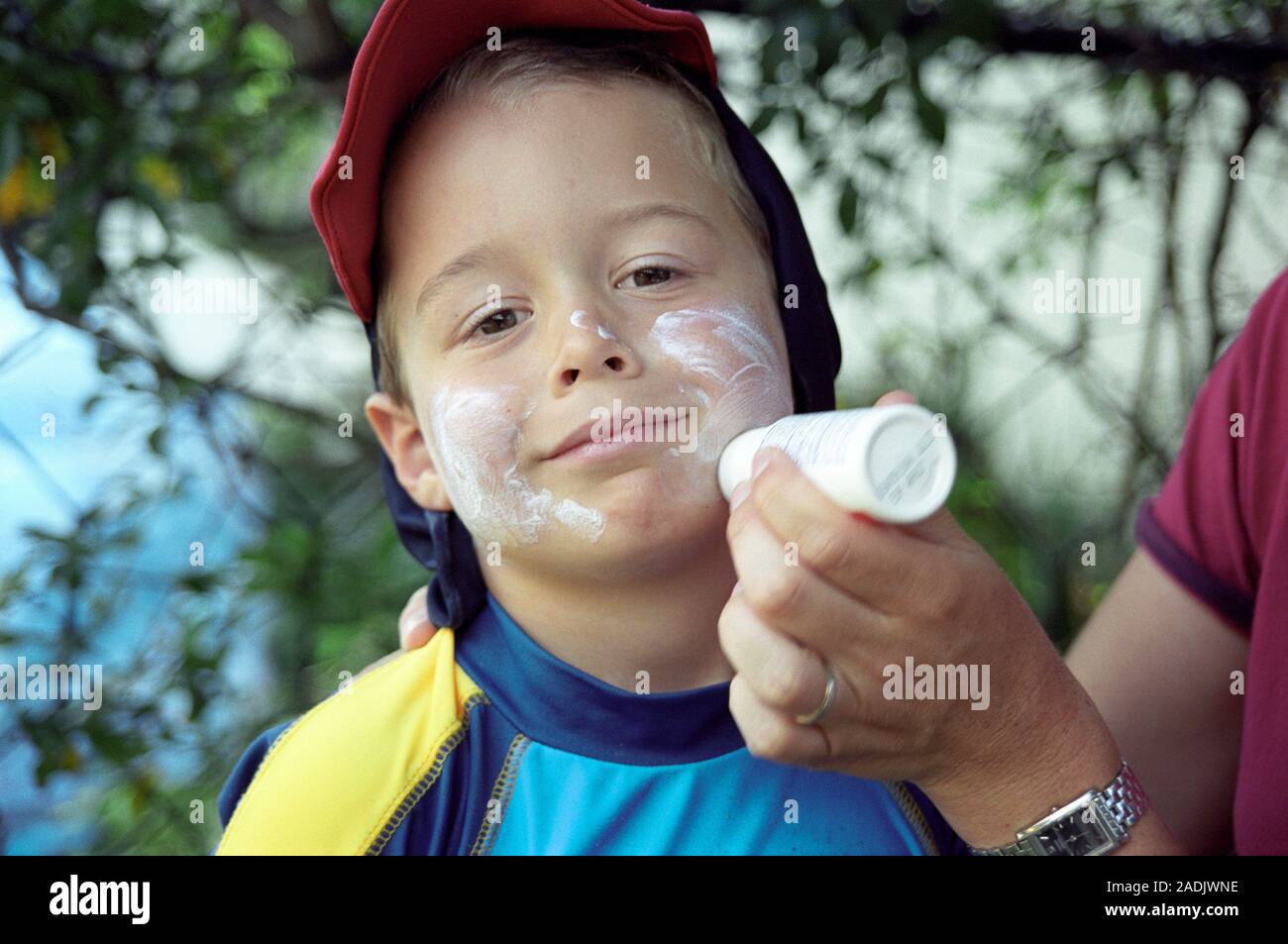 MODEL RELEASED. Sun protection. Boy wearing a sun hat and having sun ...