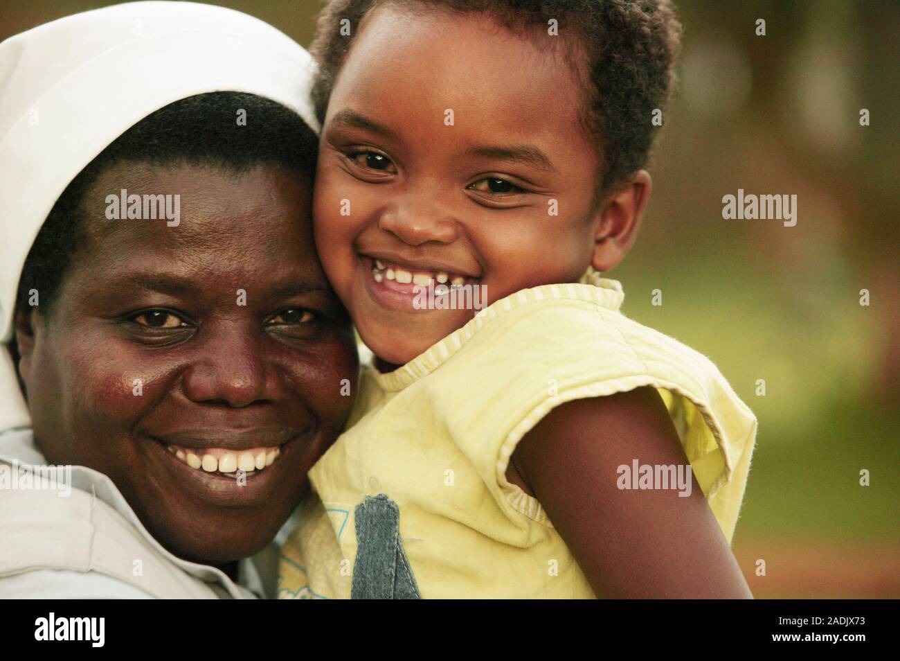 Convent childcare. Smiling nun carrying a smiling child. The child is ...