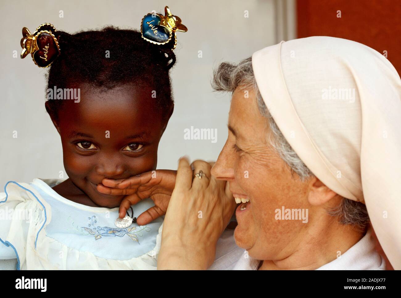 Convent childcare. Nun laughing with a smiling girl. The nun is part of ...