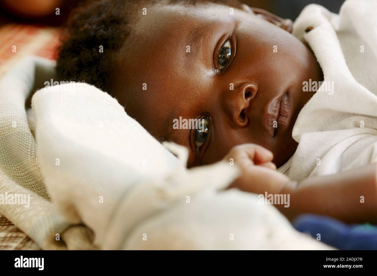 Baby resting on the floor. Photographed in the Gulu region of Uganda ...