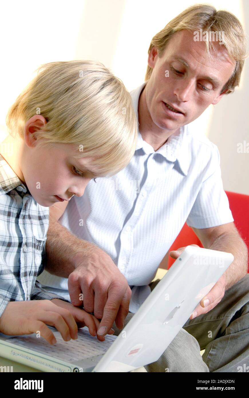 Laptop use. Father teaching his son to type on a laptop computer Stock ...