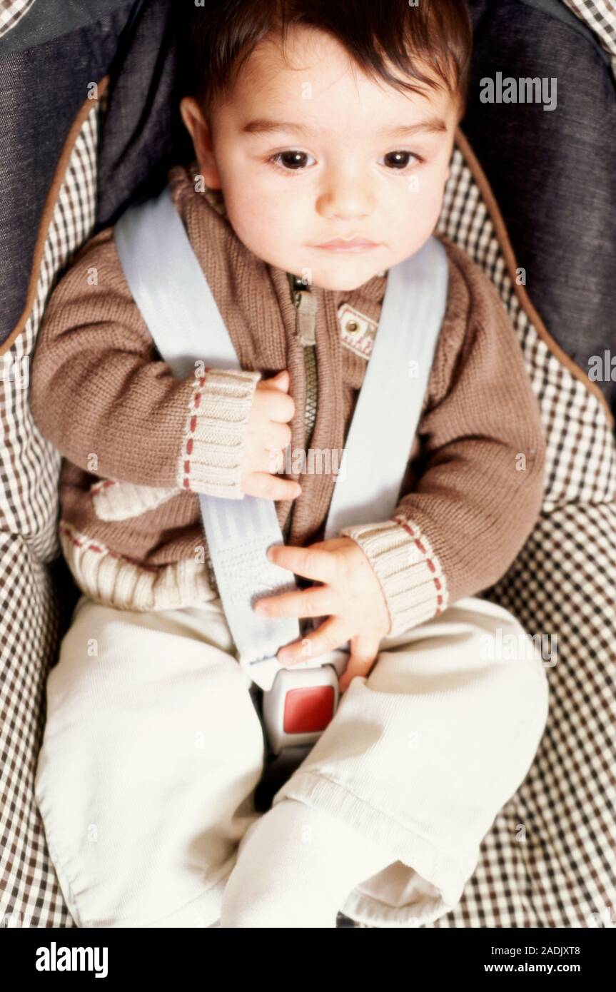 Child safety. Six-month-old baby boy strapped into a child car seat ...