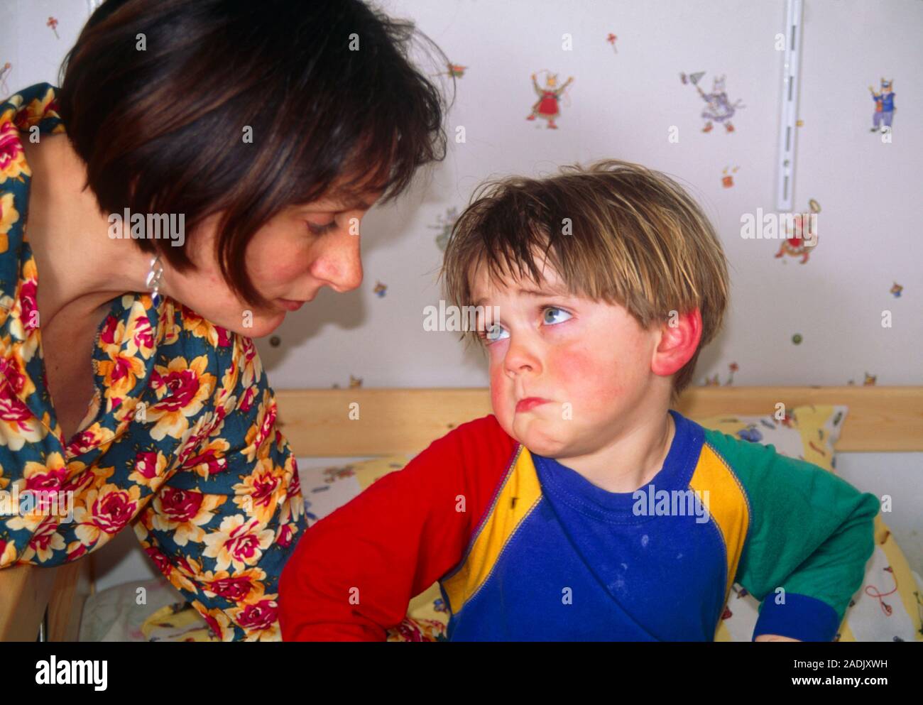 Feverish child. A flushed and sulking three year-old boy with a fever ...