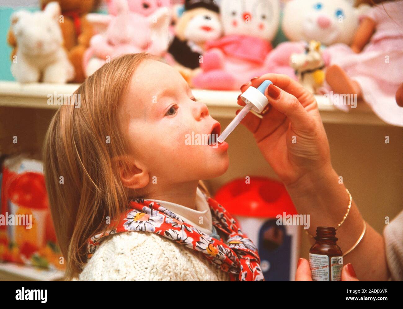 Child receiving Panadol. Young girl receives a dose of Panadol by mouth ...