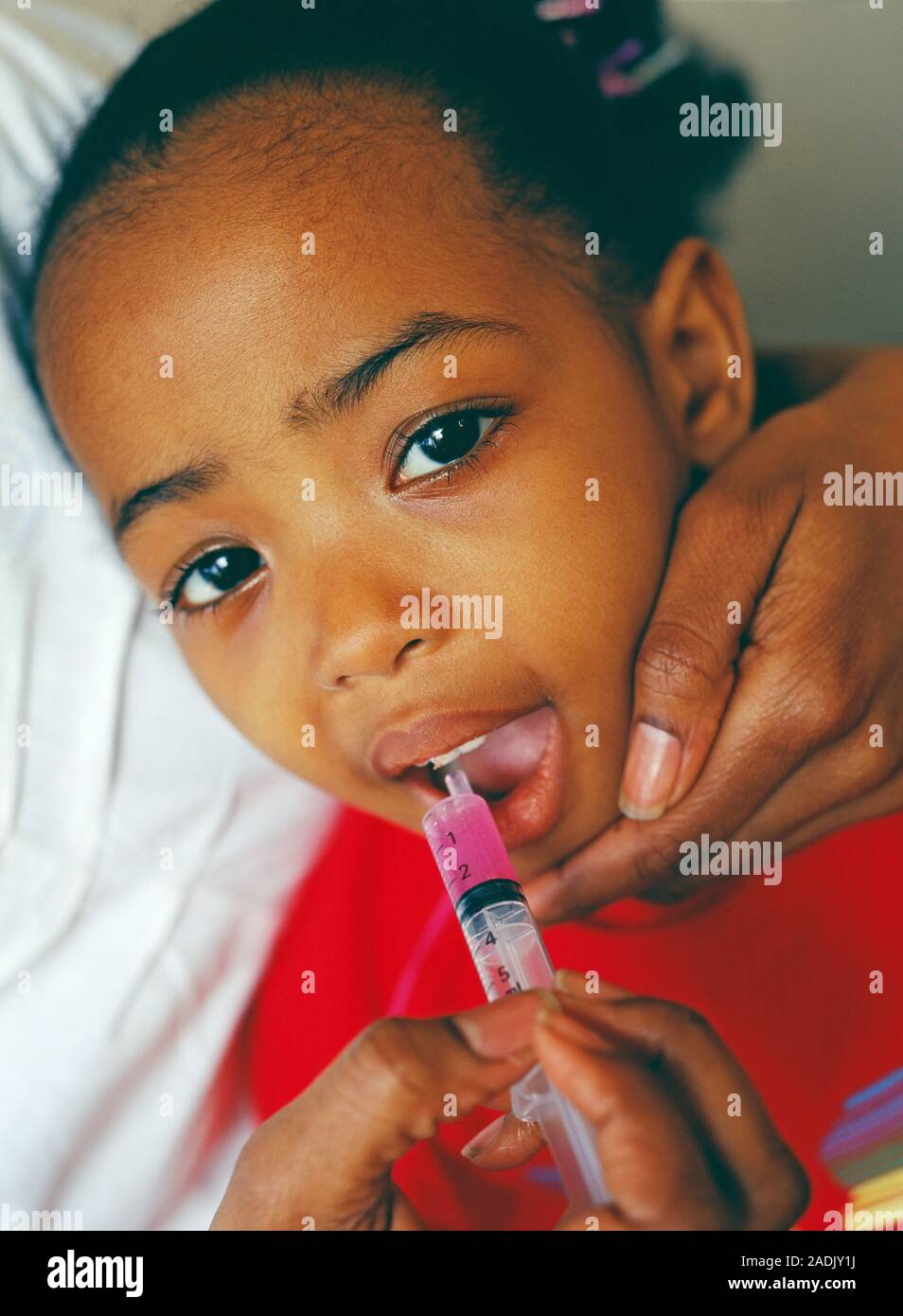 Syringe of medicine being given to an ill four-year-old girl by her ...