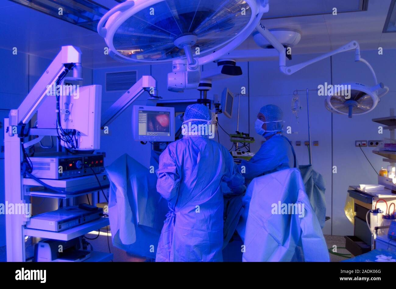 Ovarian cyst removal. Surgeons looking at a display on a screen during ...