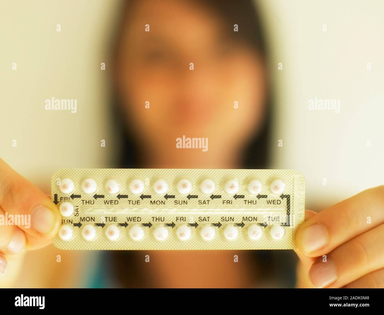 Oral contraceptive pills in their packaging, being held by a woman. The ...