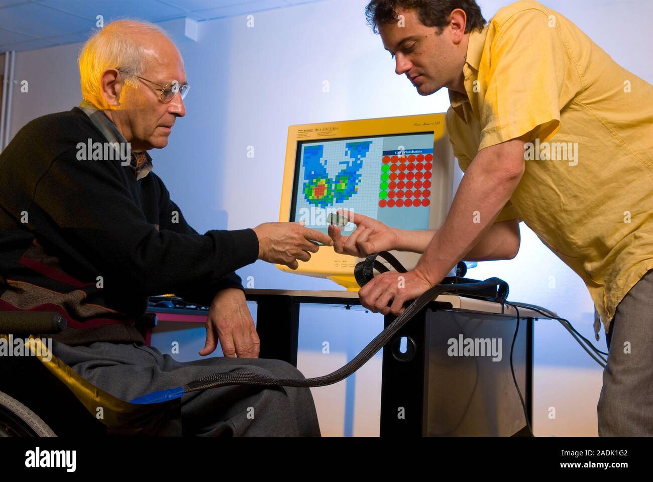 Paraplegic with Tongue Display Unit. Researcher (right) handing a ...