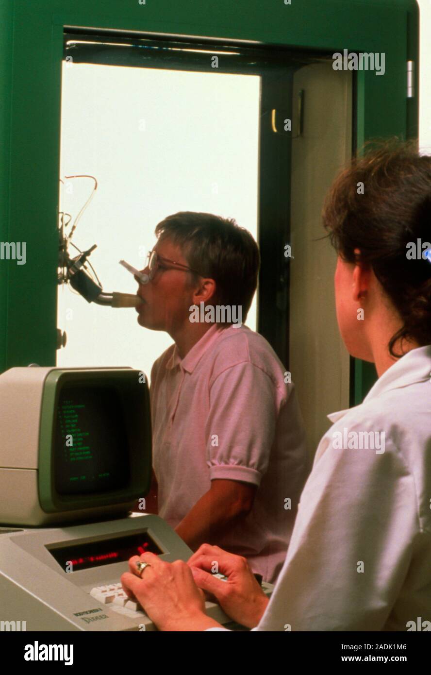 Testing lung function. A woman breathing into a peak flow meter ...