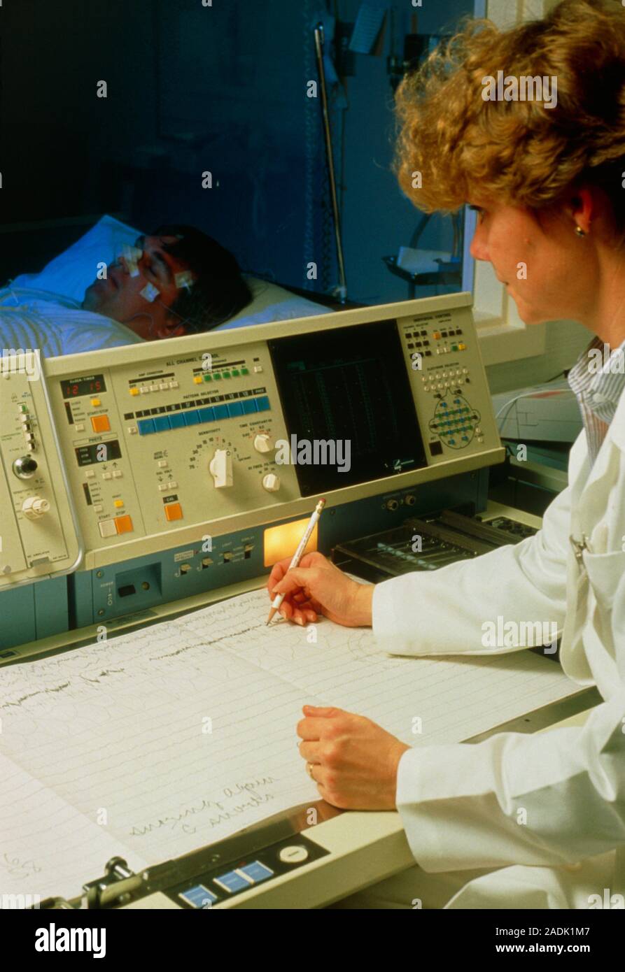 Sleep research. Male patient (in the background) is wired up to ...