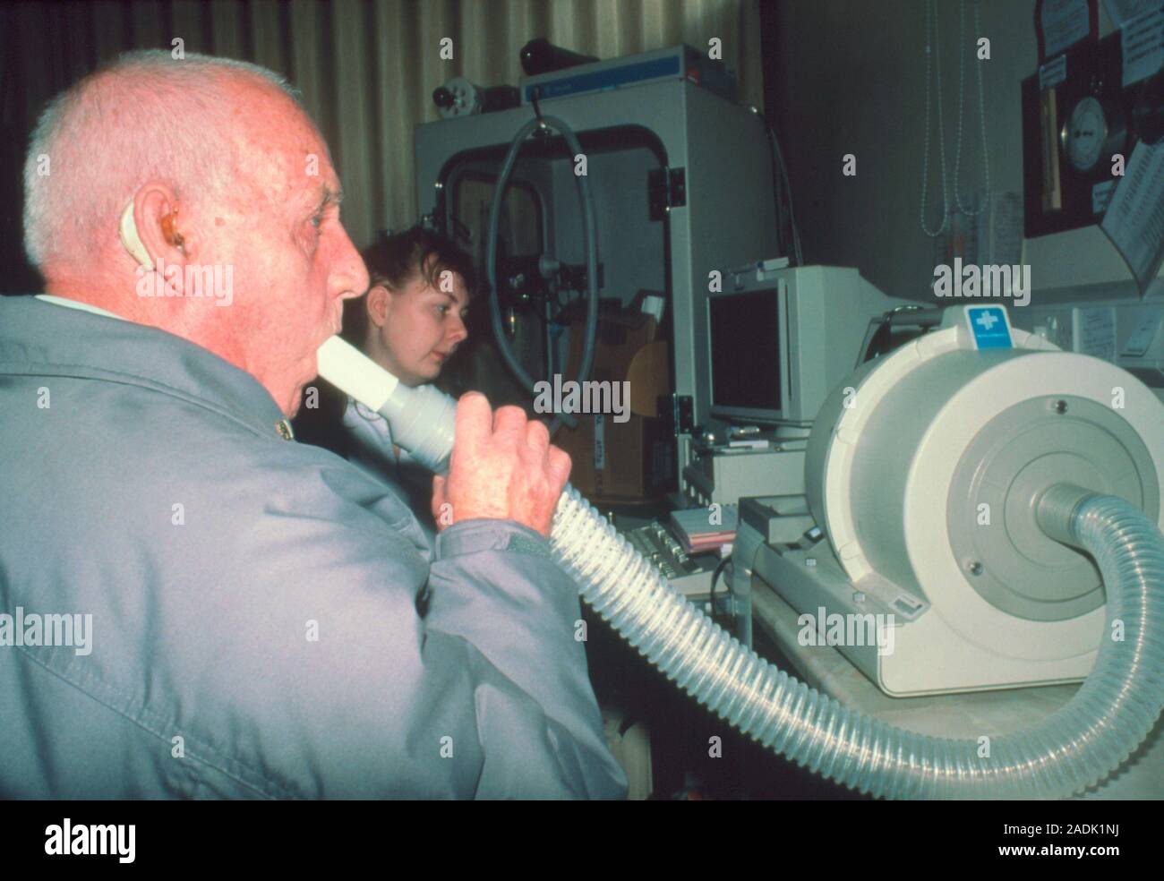 Lung function test. Elderly man blows into the mouthpiece of a ...