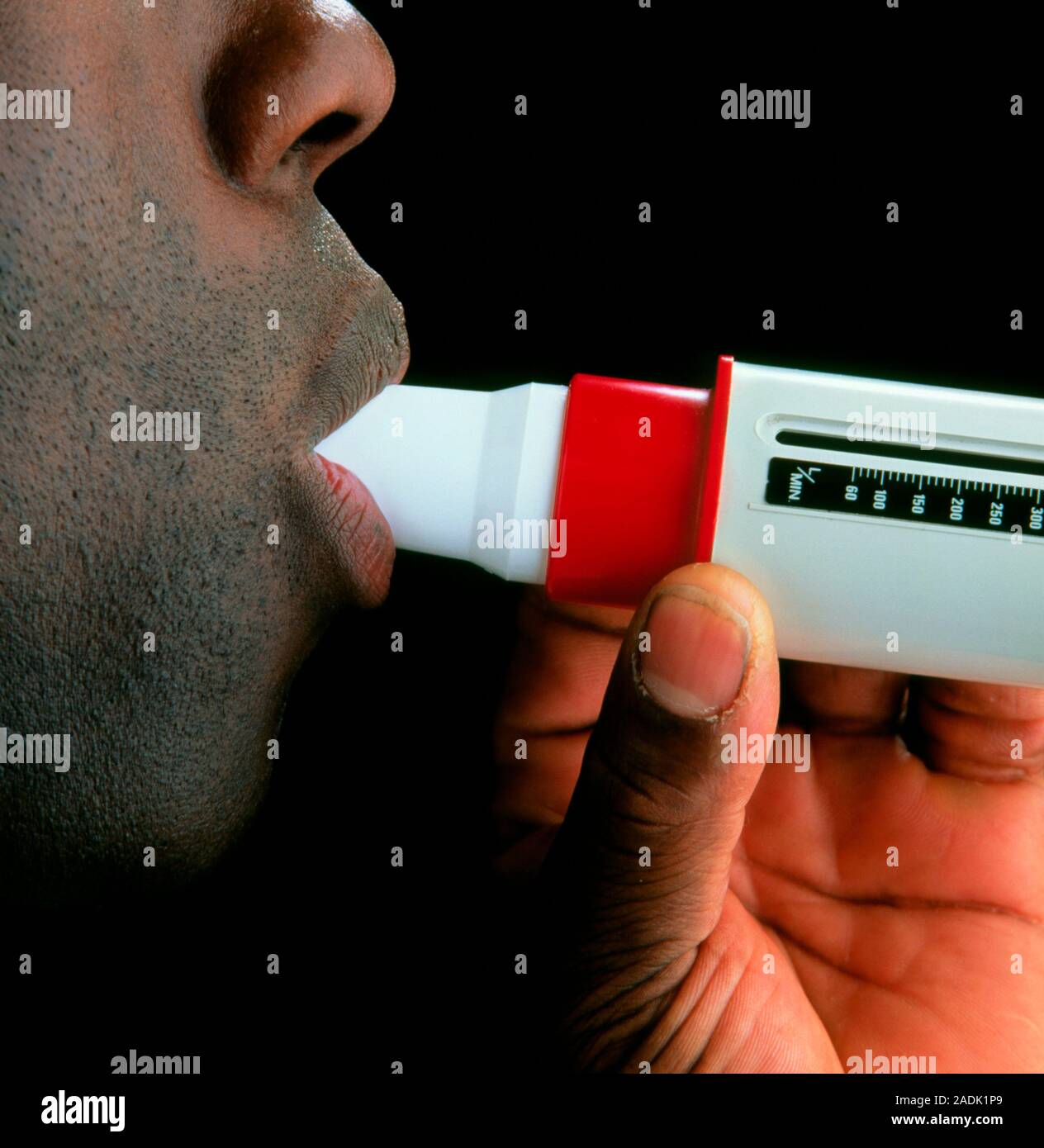 Lung function test. Man breathing out through a peak flow meter. This ...