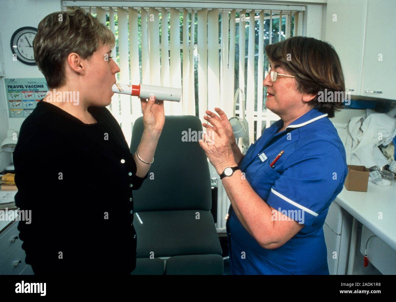 Lung function test. Woman breathing out through a peak flow meter ...