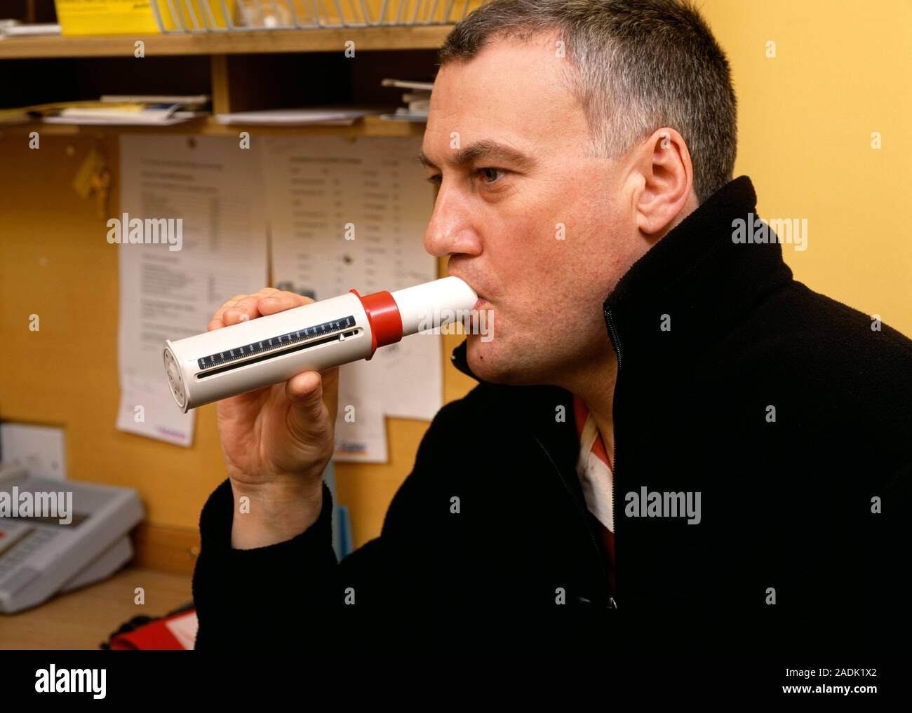 MODEL RELEASED. Lung function test. Man breathing into a peak flow ...