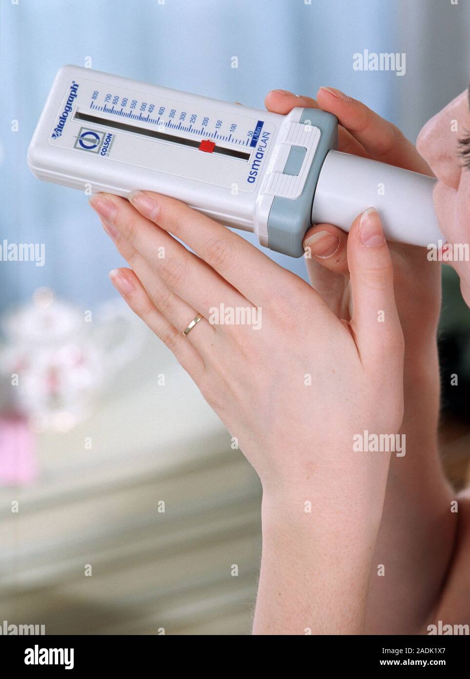 Lung function test. Woman breathing into a peak flow meter (spirometer ...