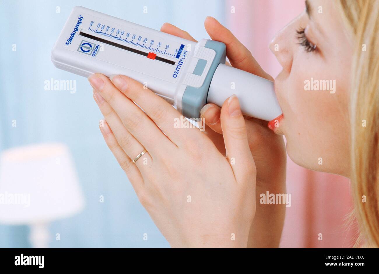 MODEL RELEASED. Lung function test. Woman breathing into a peak flow ...