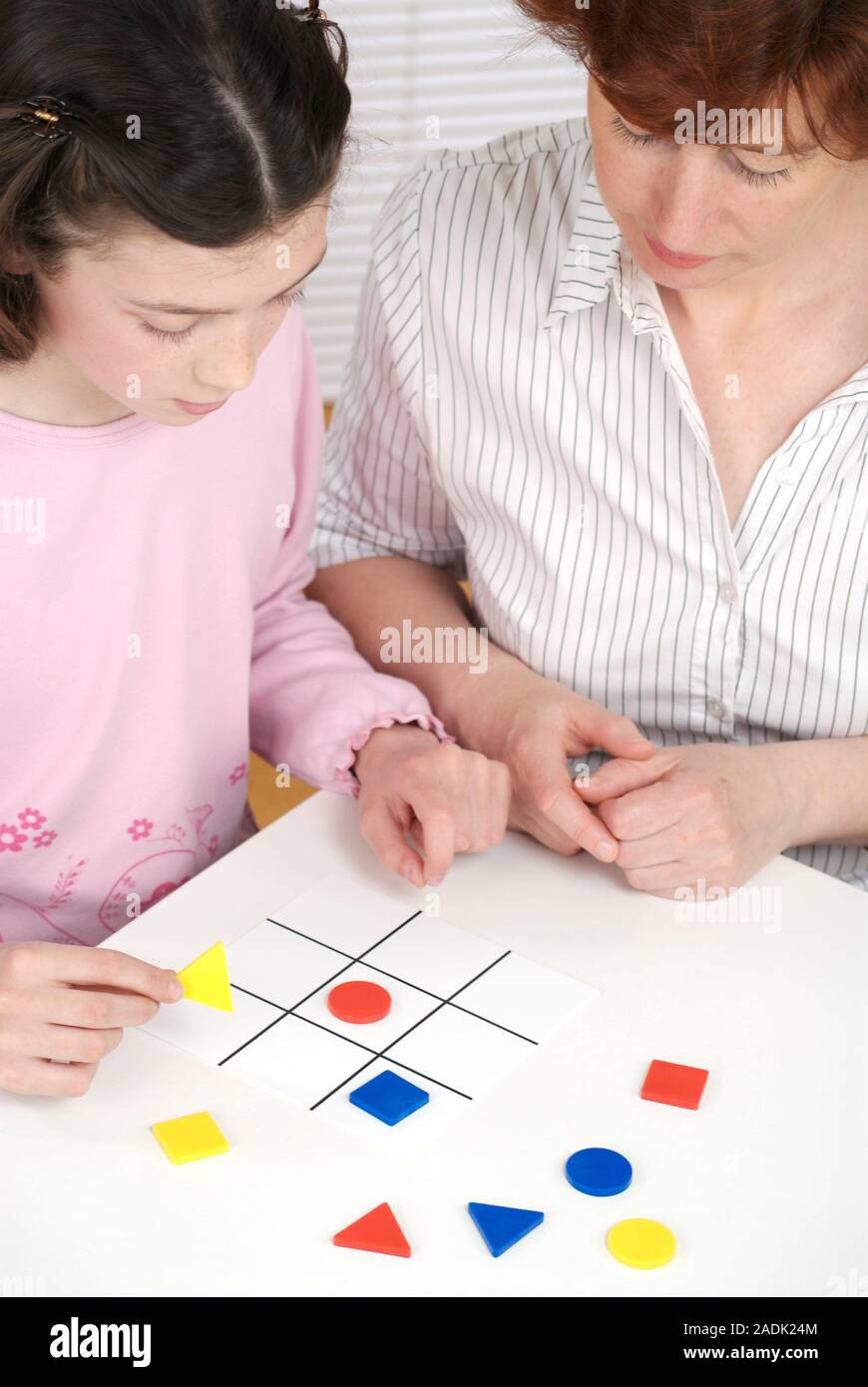 Logic game. Child psychologist with a girl who is playing a logic game ...