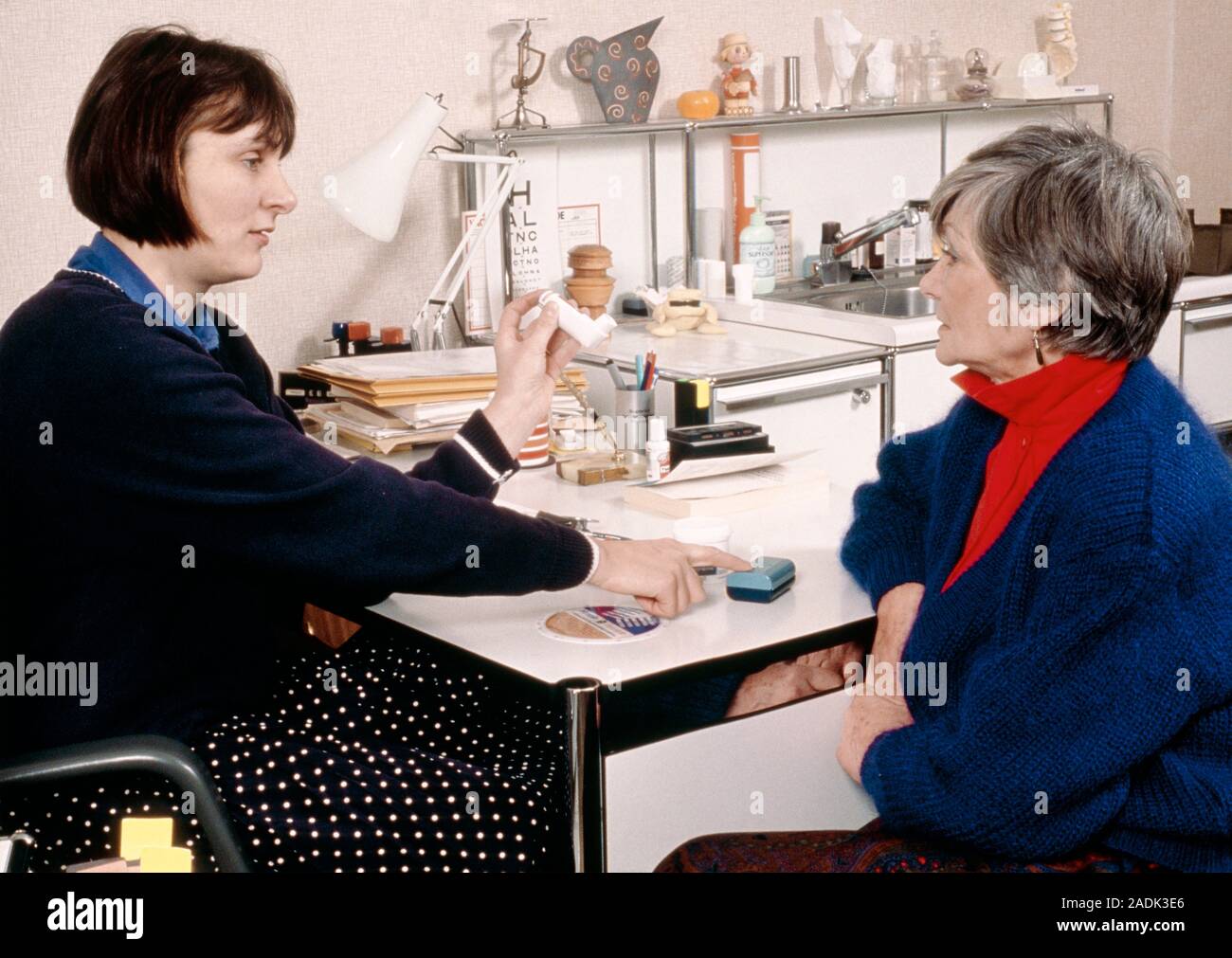 General practice doctor demonstra- ting asthma inhalers to an elderly ...
