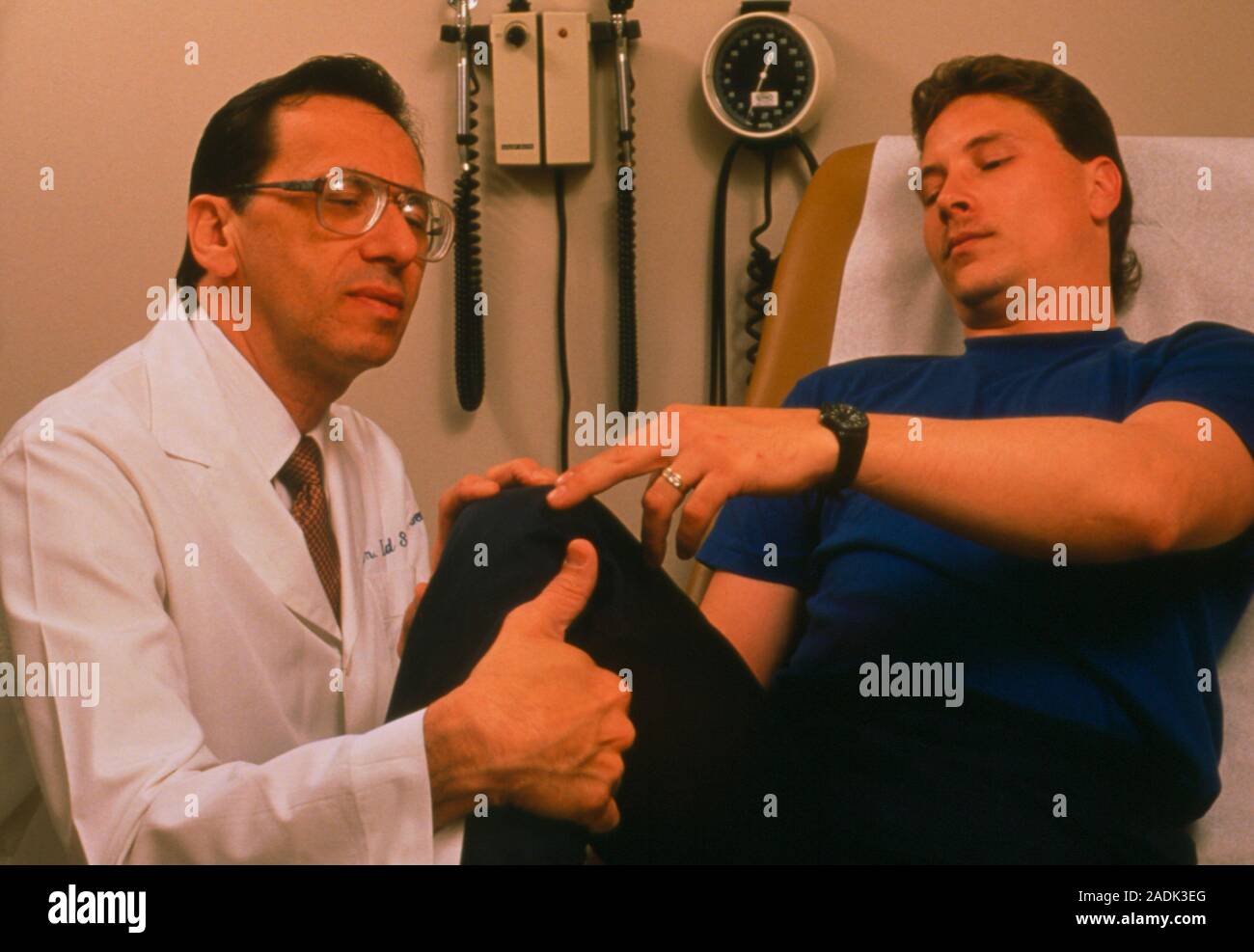 General practice doctor examines the knee joint of a male patient. The ...