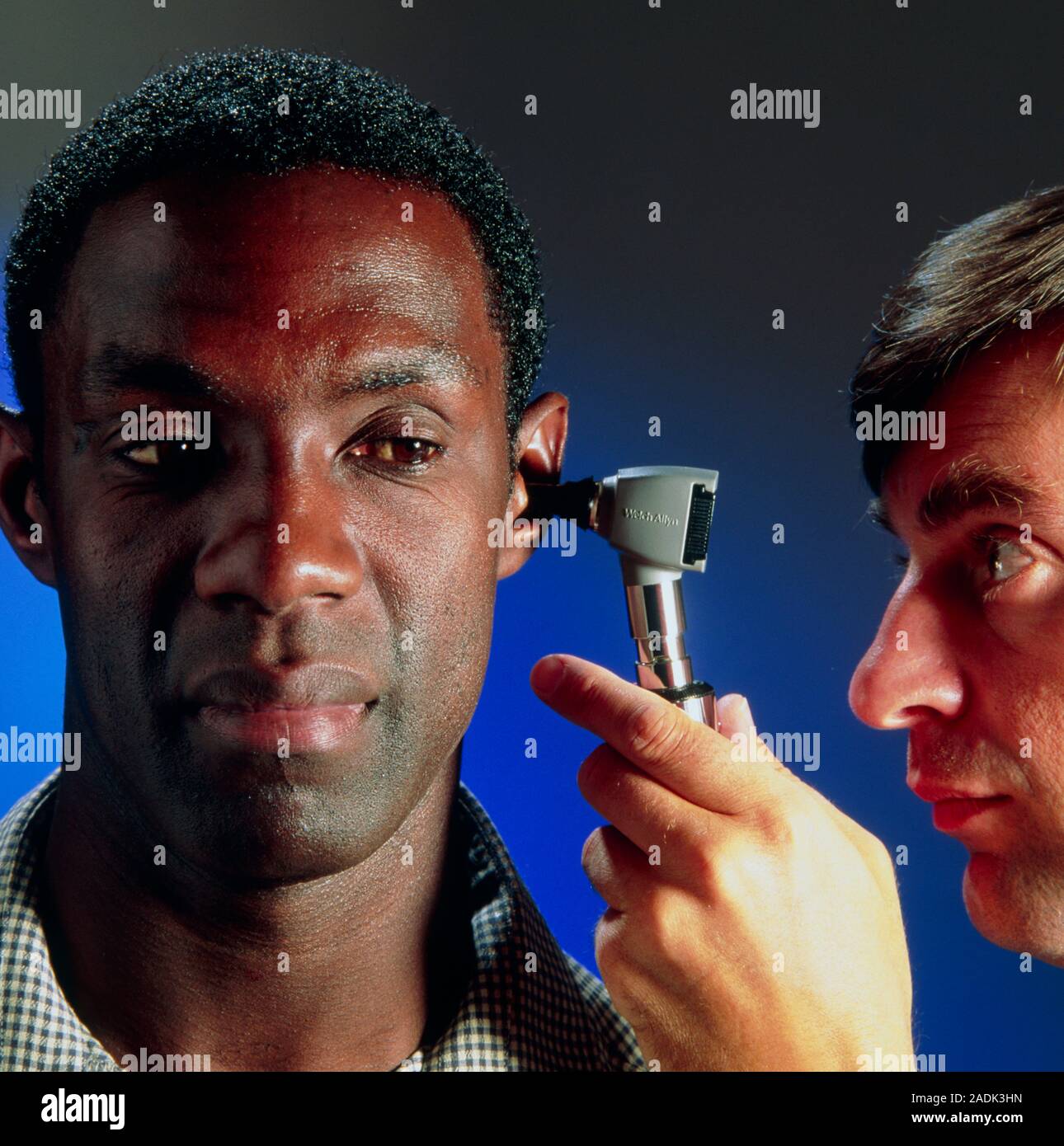 Ear examination. Doctor performing a routine ear examination on a man ...