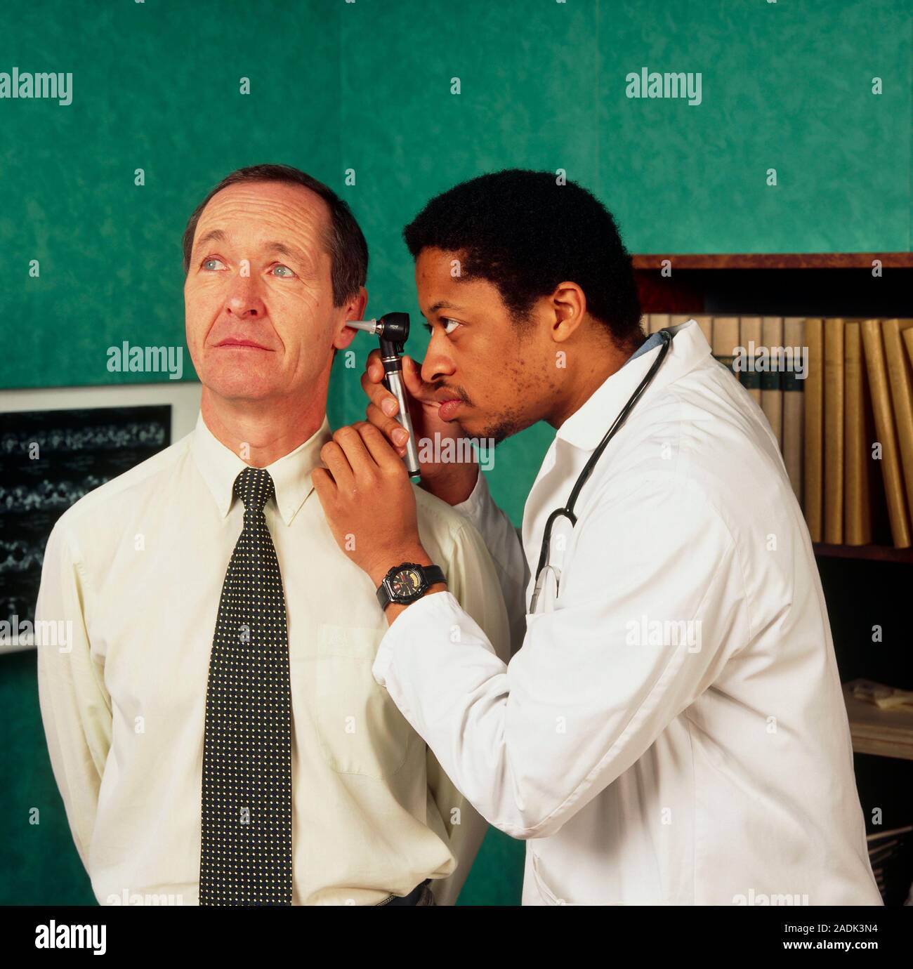Ear examination. General practice (GP) doctor performing an ear ...