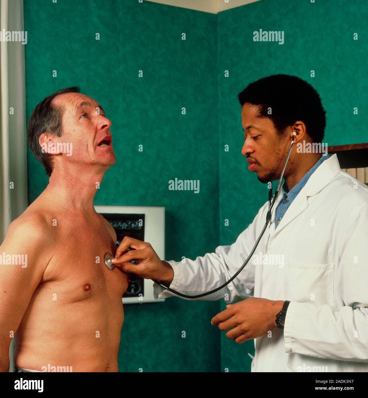 Chest examination. General practice (GP) doctor listening to a man's ...