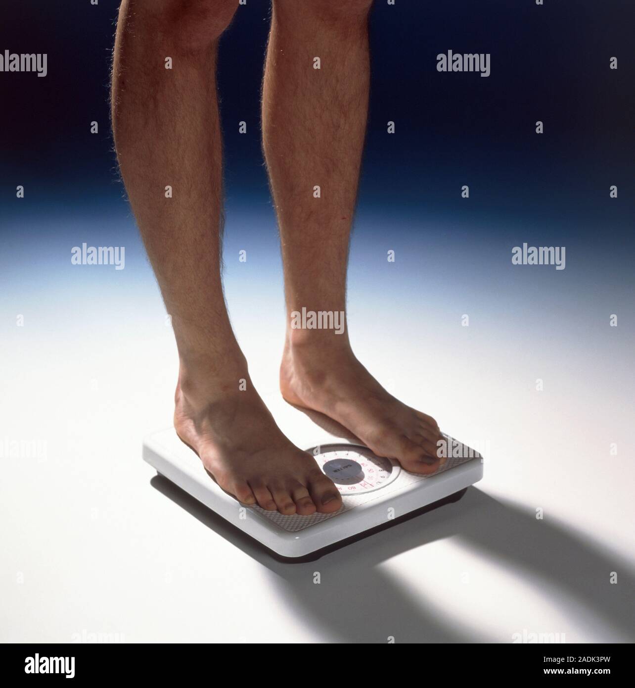 Man on weighing scales. View of a man's legs standing on a set of ...