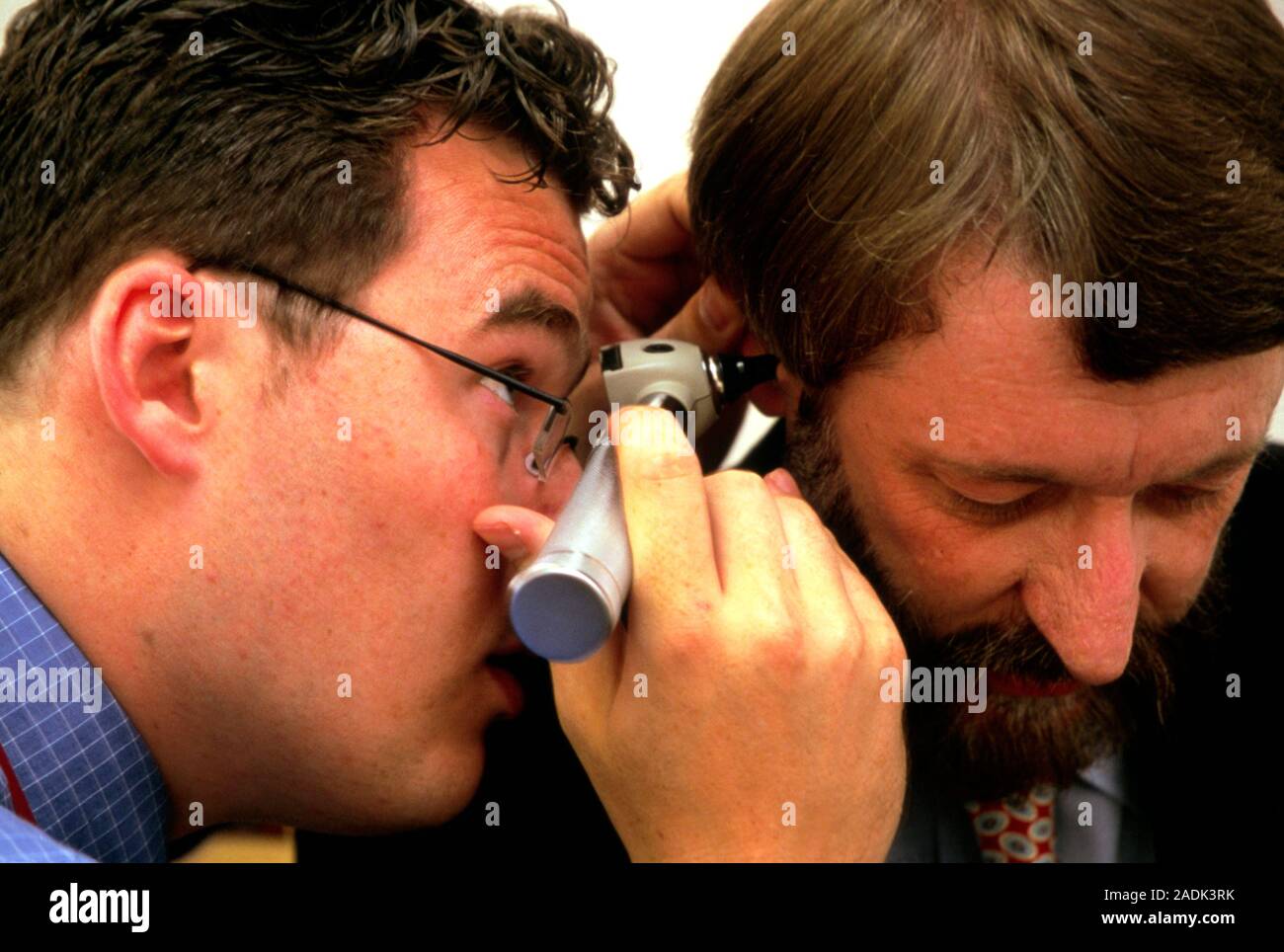 Ear examination. General practice doctor checking a male patient's ear ...