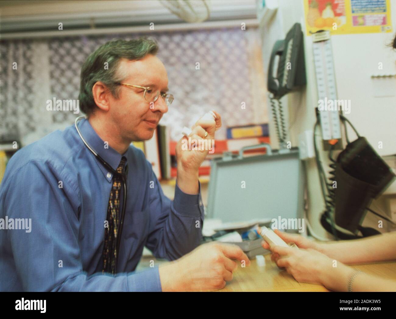 Consultation. Doctor demonstrating an asthma inhaler use to a patient ...
