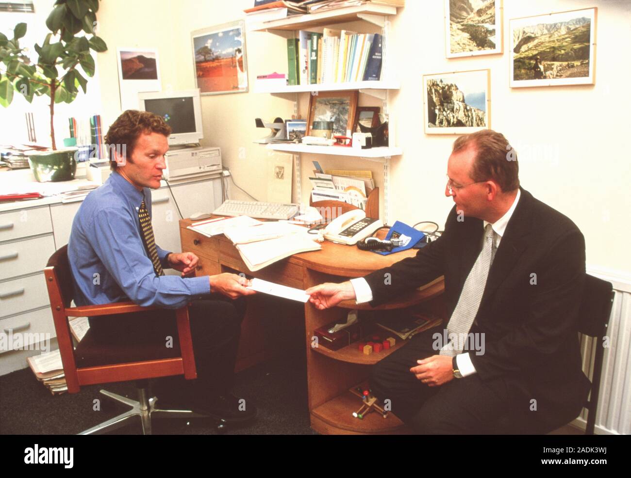General practice (GP) doctor handing a health leaflet to a patient ...