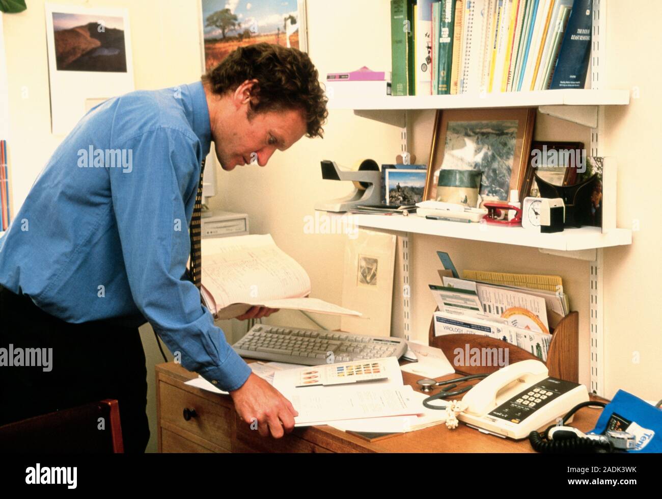 General practice (GP) doctor reading a patient's notes and consulting ...