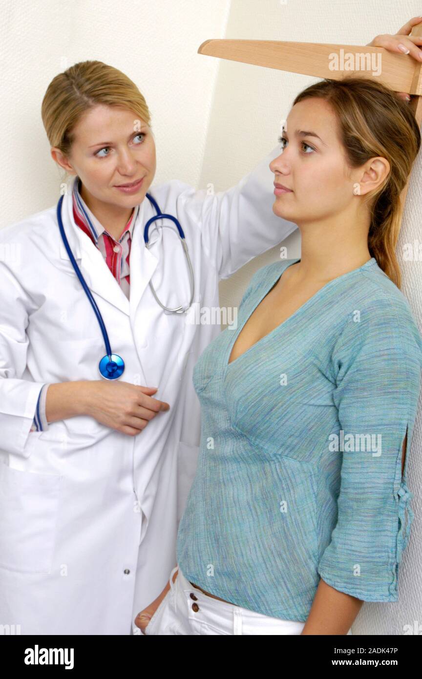 MODEL RELEASED. Height measurement. General practitioner measuring a ...