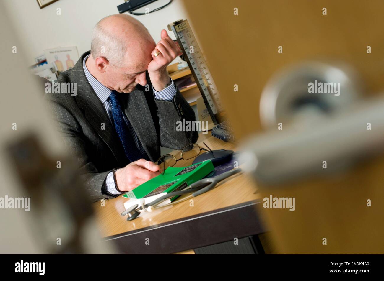 MODEL RELEASED. Tired doctor. General practitioner (GP) rubbing his ...
