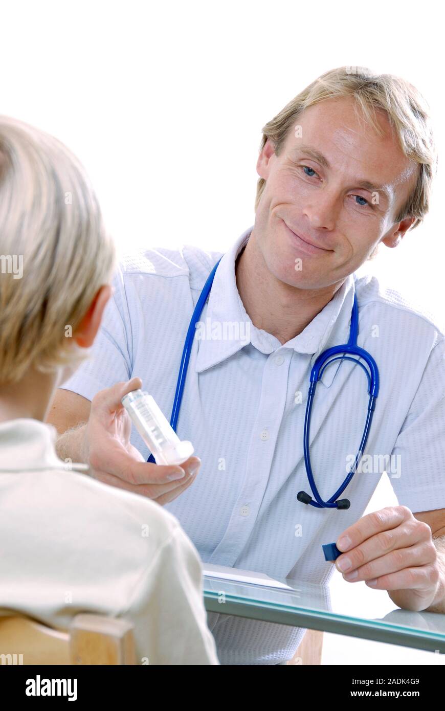 Inhaler demonstration. Doctor showing an asthmatic boy how to use an ...