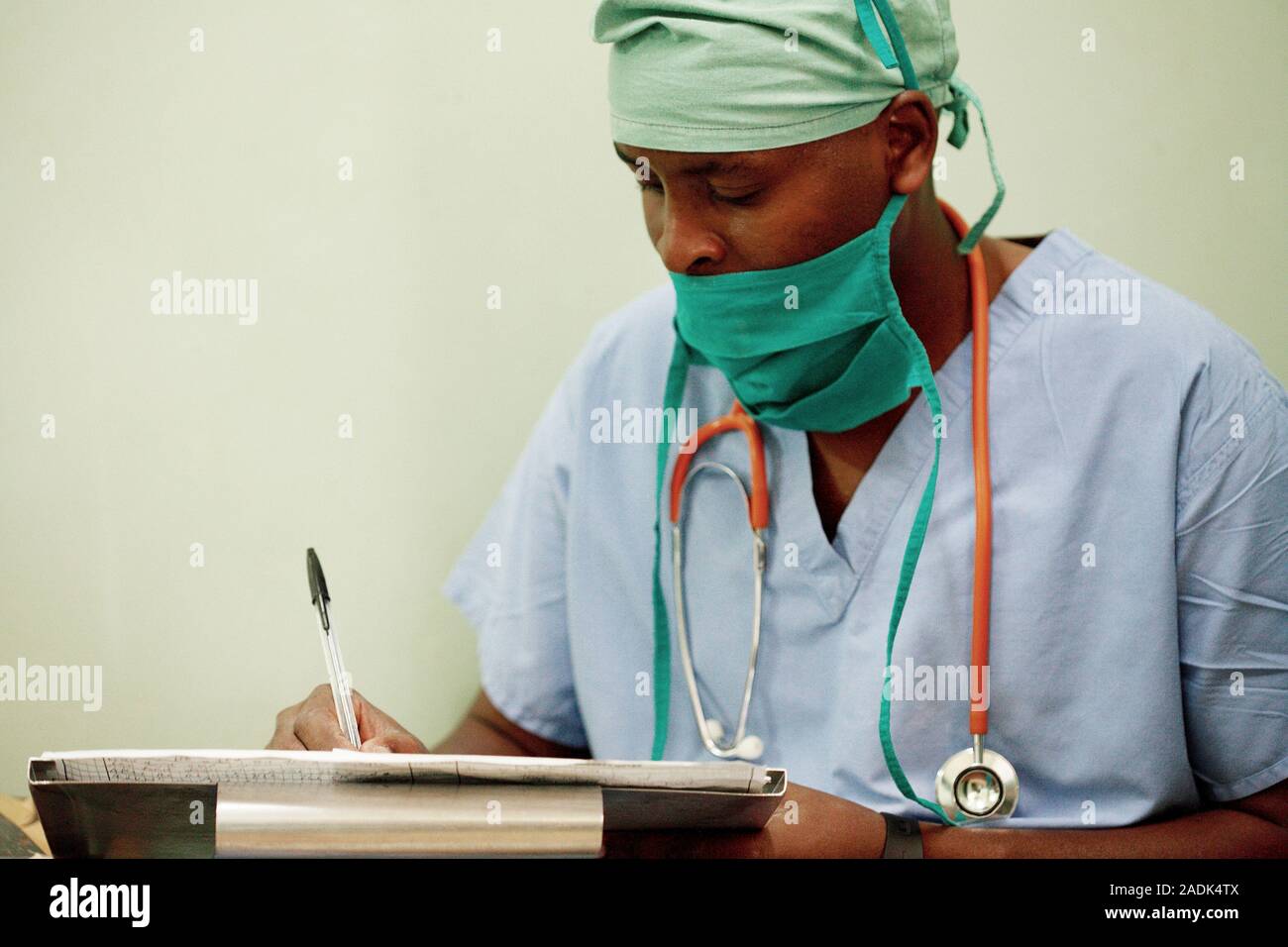 MODEL RELEASED. Theatre assistant writing notes into a medical record ...
