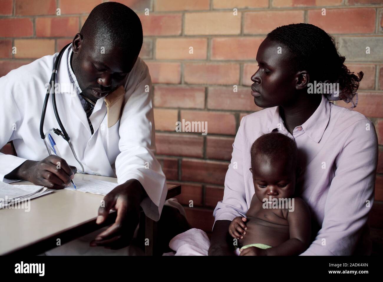 MODEL RELEASED. Assessing a sick child. Doctor making notes after ...