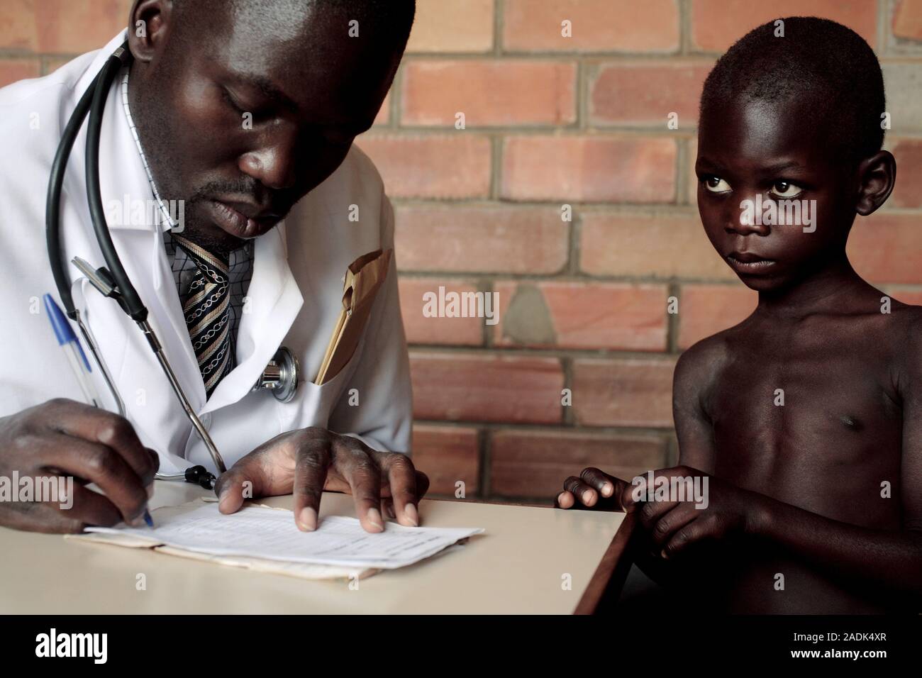 MODEL RELEASED. Assessing a sick child. Doctor making notes after ...