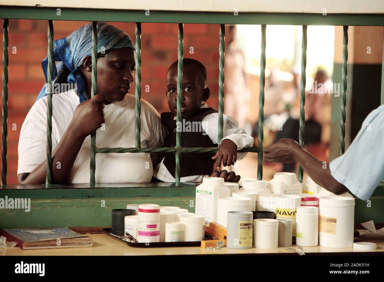 MODEL RELEASED. Dispensing medication. Mother and child waiting behind ...
