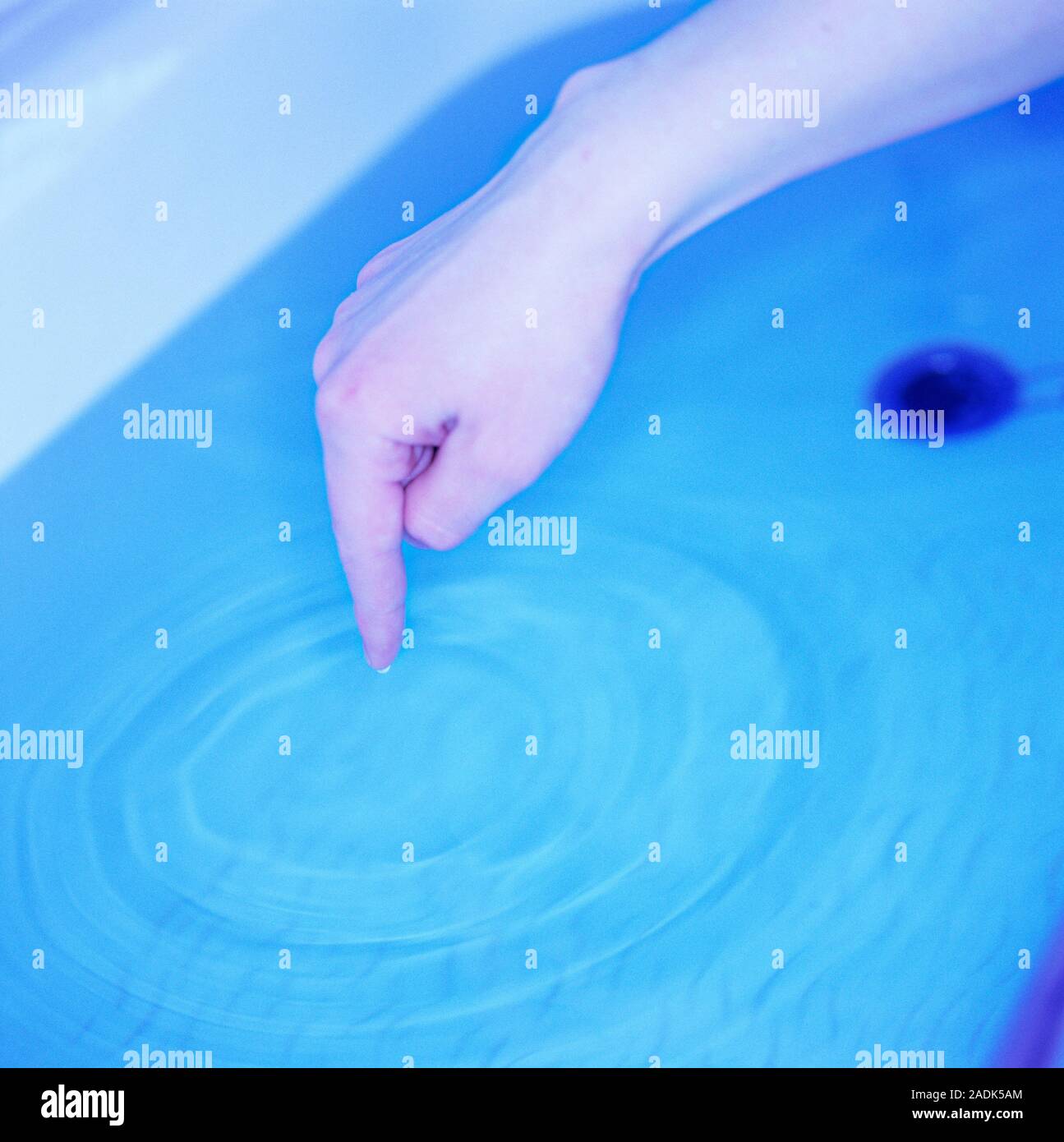 Water temperature testing. Finger is dipped in a bath tub full of water ...