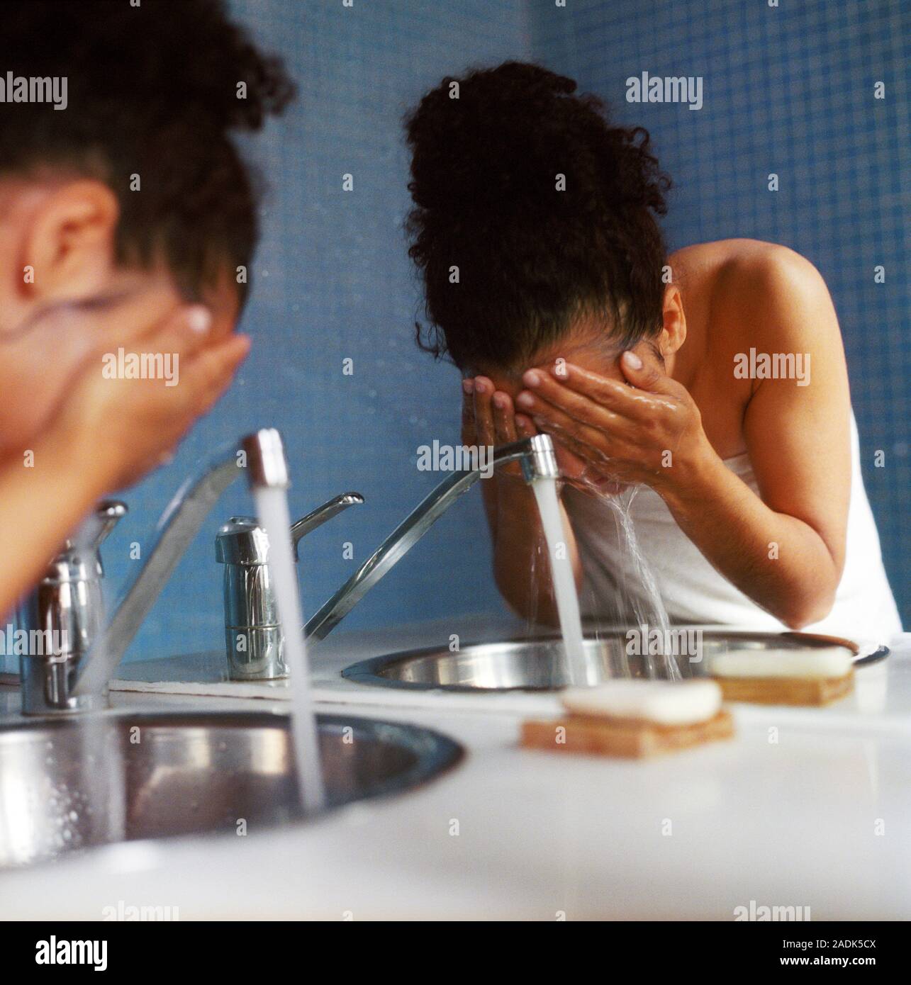 MODEL RELEASED. Woman rinsing her face at a sink Stock Photo - Alamy