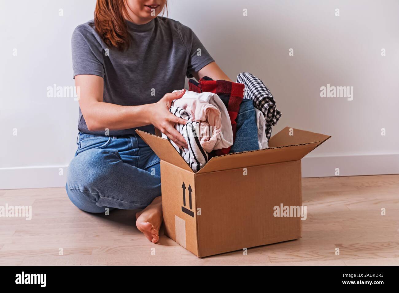 Unrecognizable woman putting clothes in cardboard box Stock Photo - Alamy