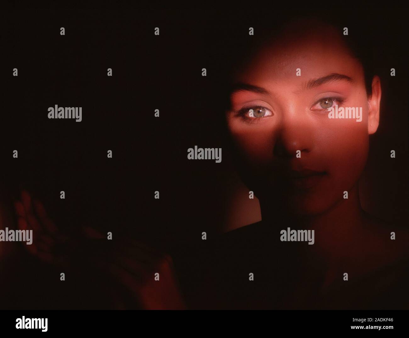 MODEL RELEASED. Eyes. Woman in shadows with light playing on her eyes ...