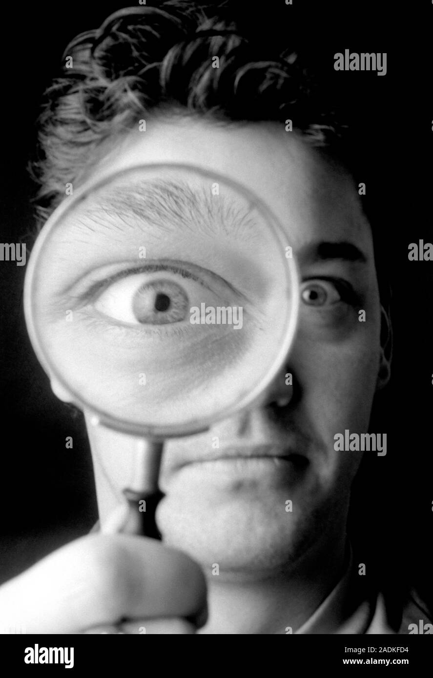 MODEL RELEASED. Magnified eye seen through a magnifying glass Stock ...
