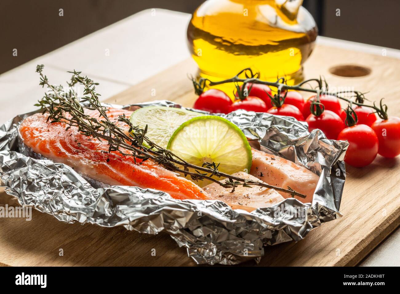 Raw red fish in foil and cherry tomatoes near Stock Photo - Alamy