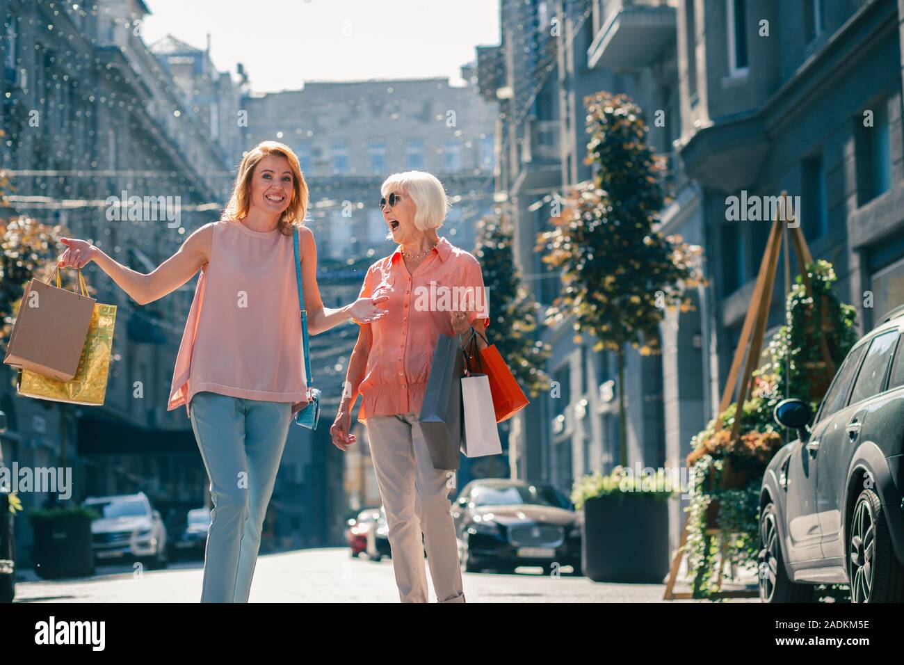 Two excited ladies walking with paper bags and laughing Stock Photo - Alamy
