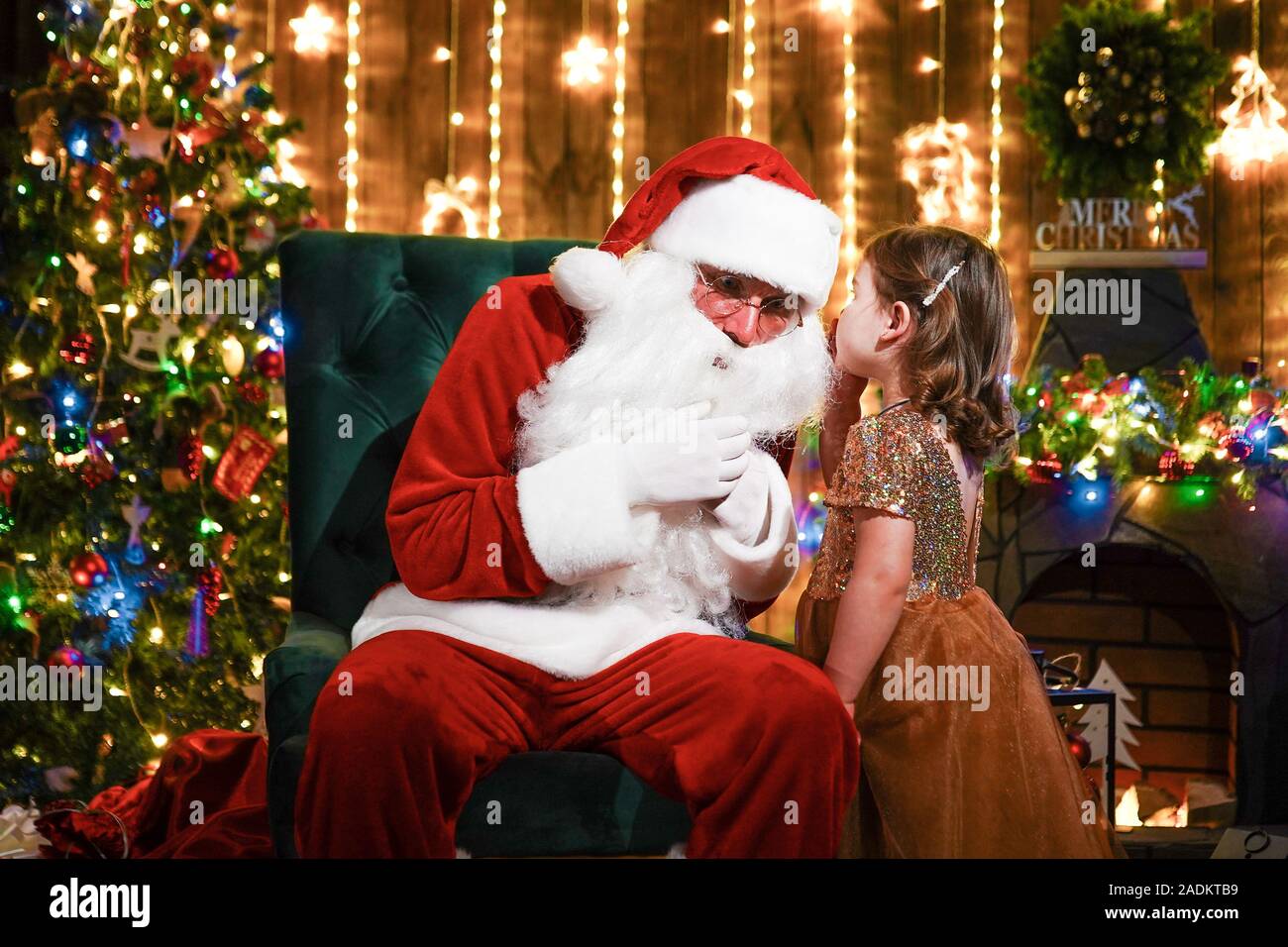 Little girl whispering in Santa's ear. Telling a secret. Revealing the ...