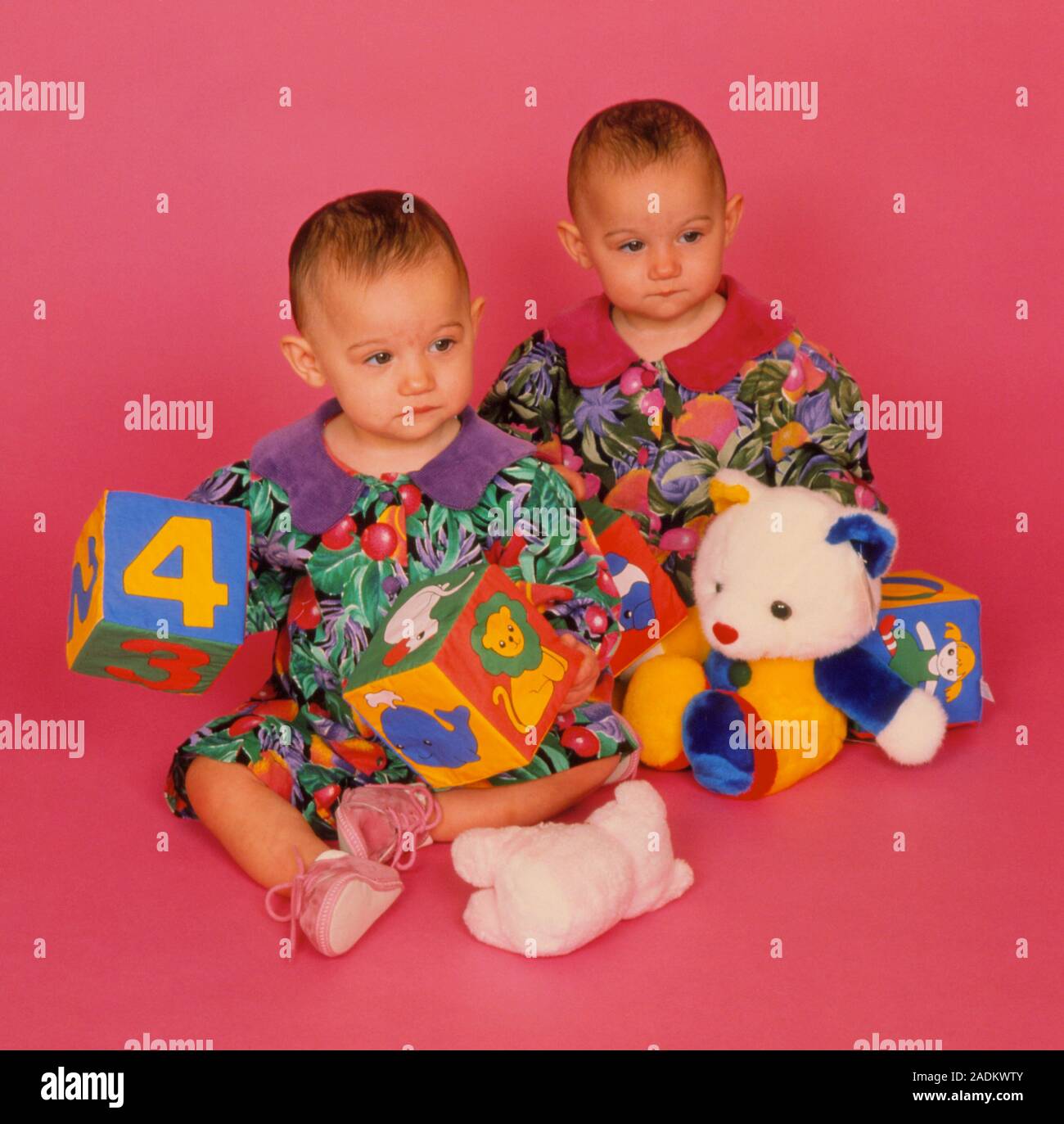 Identical twins. Infant identical twins, one year old girls, sitting ...