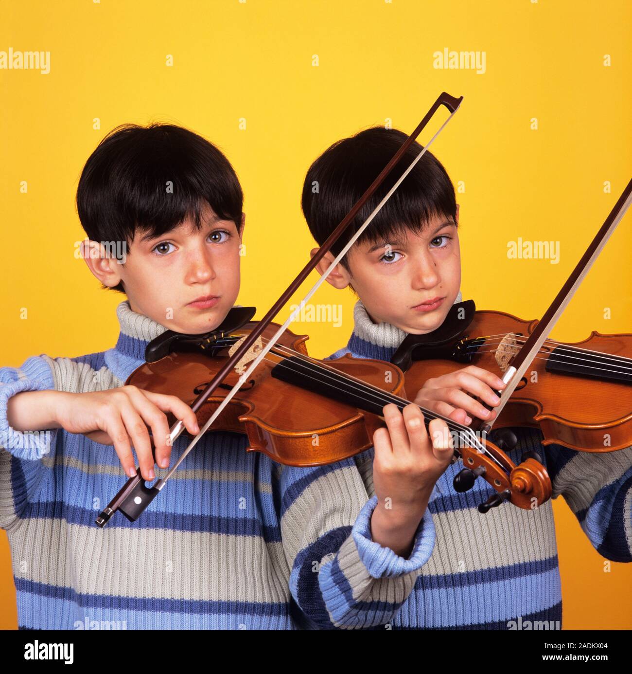 Identical twin sisters playing the violin. Genetically identical ...