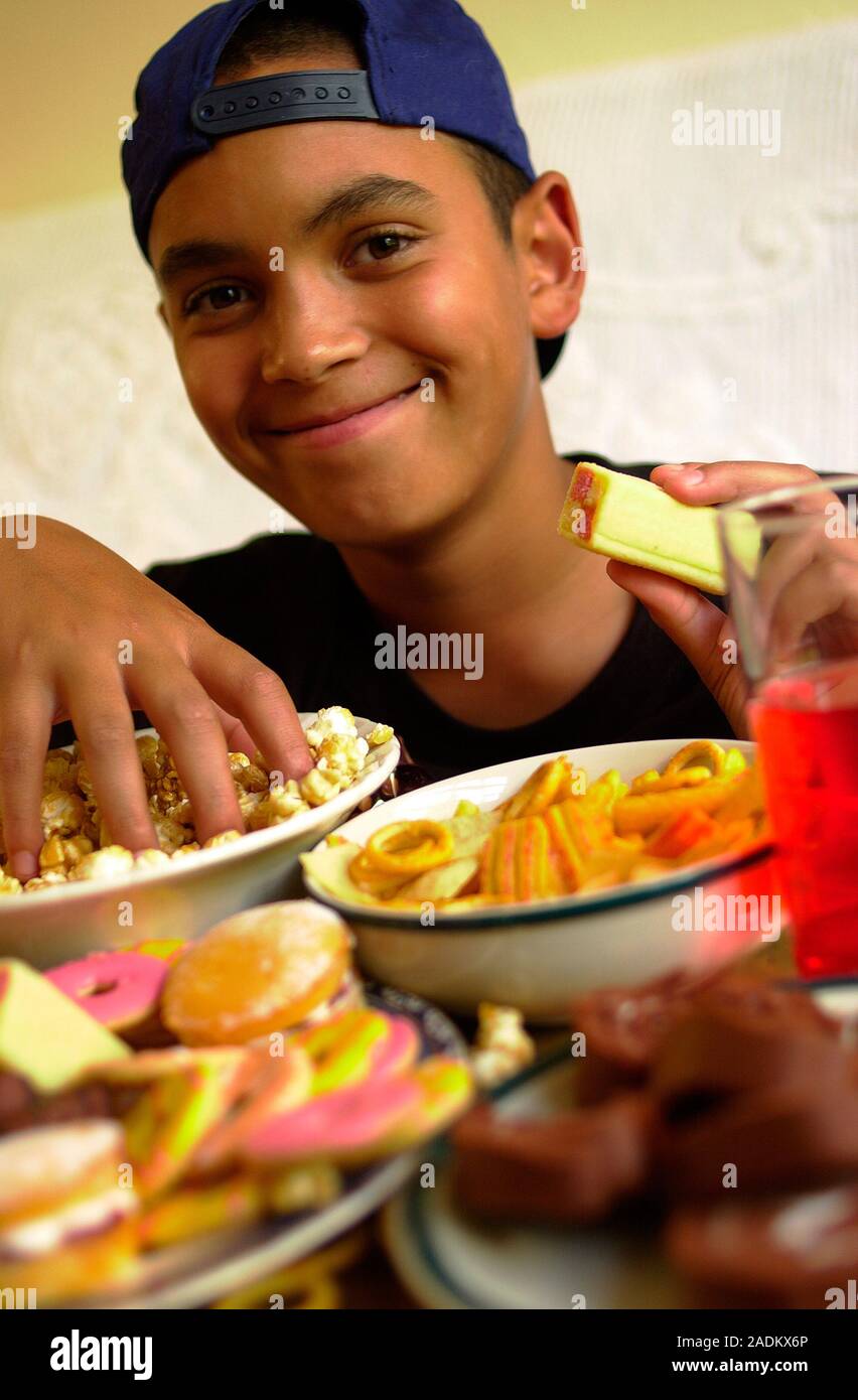 Junk food. Teenage boy smiling as he takes a handful of popcorn from a ...
