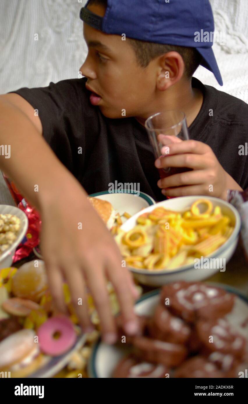 Junk food. Teenage boy sneakily reaching for a piece of cake. Junk ...